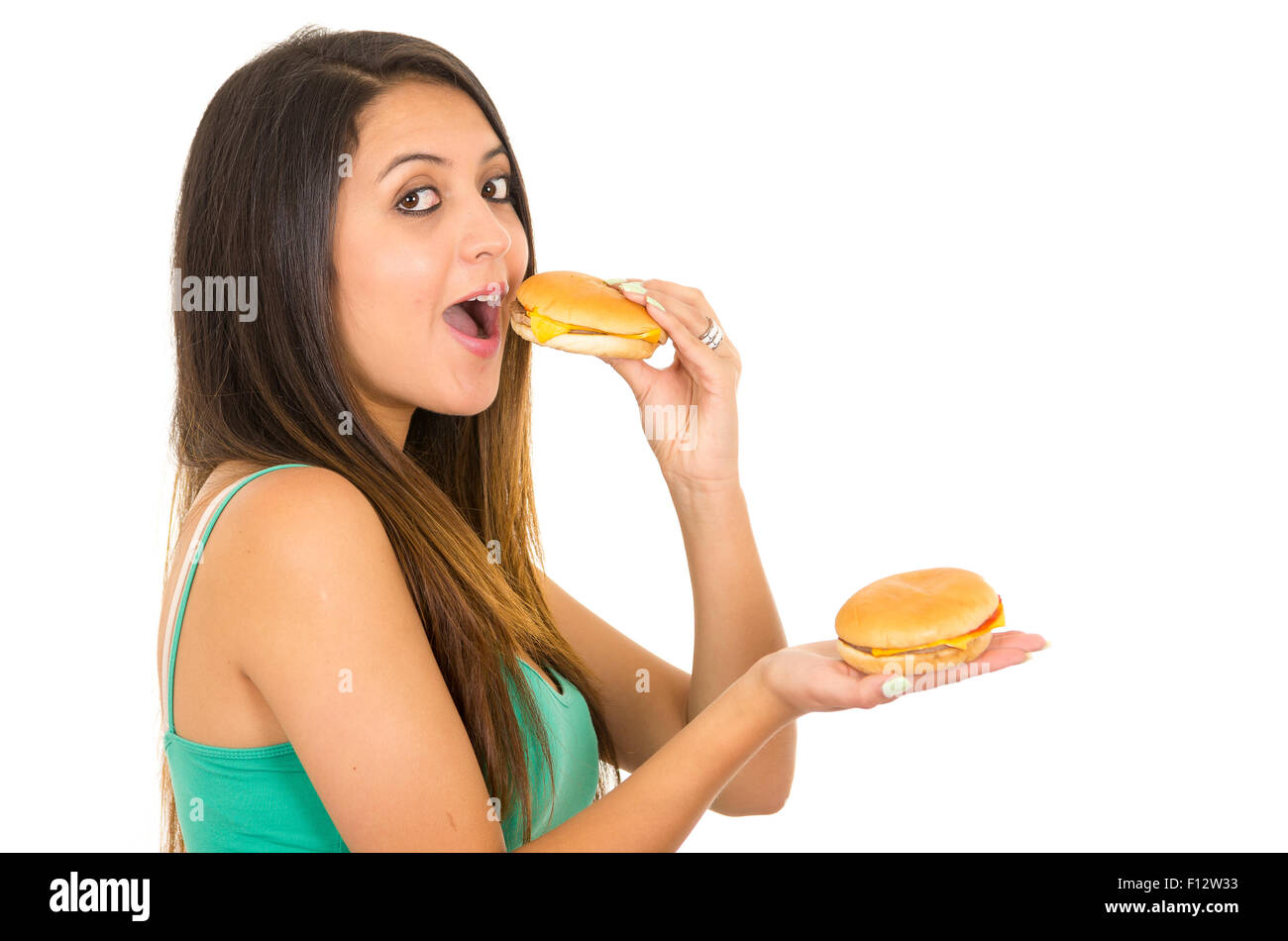 Hispanic brunette model wearing turquoise top eating hamburger with one ...