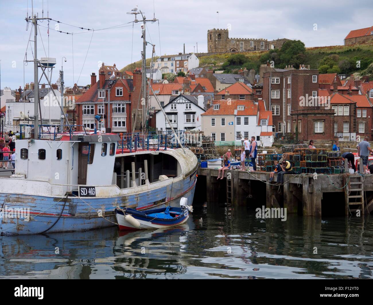 Fishing boats sitting in Whitby harbor with a church and houses in the ...