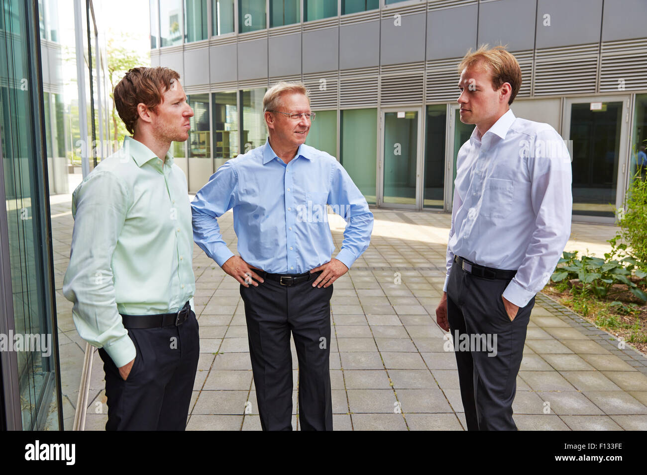 Three business people standing outside and talking during lunch break ...