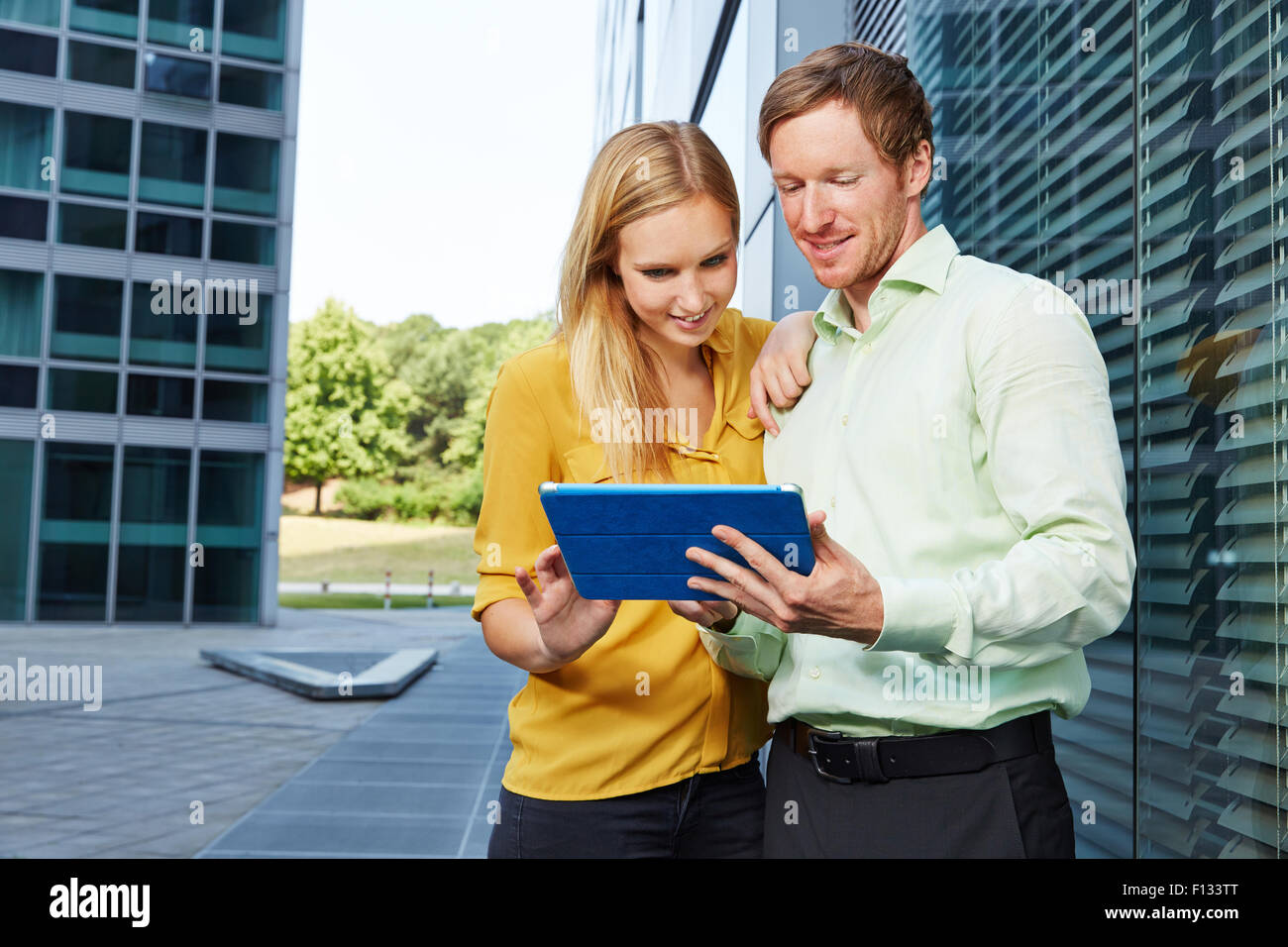 Two young business people using internet connection with a tablet ...