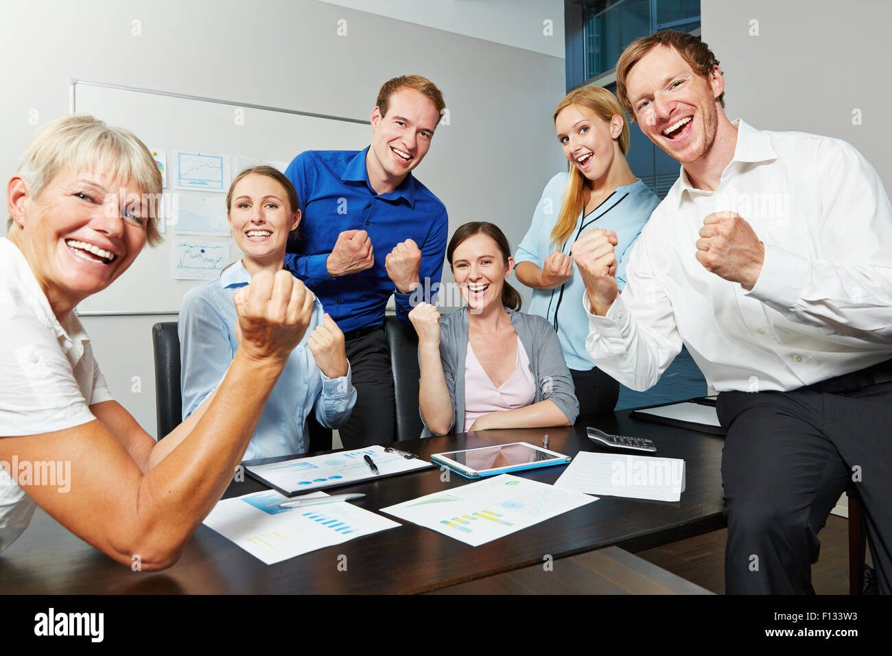 Cheering business people motivating with clenched fists in the office ...