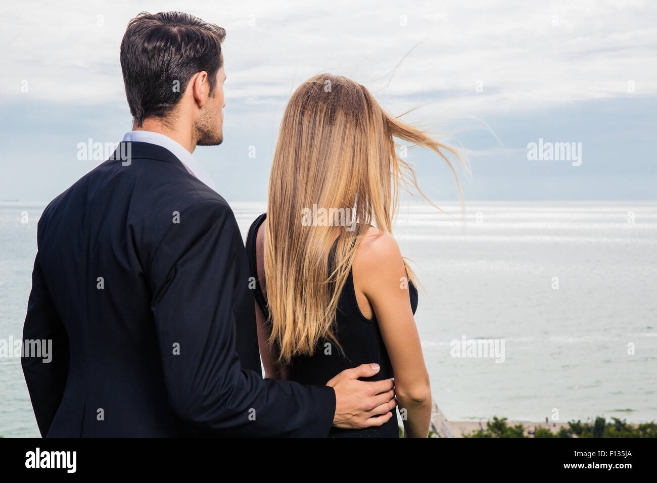 Back view portrait of romantic couple standing outdoors and looking at ...