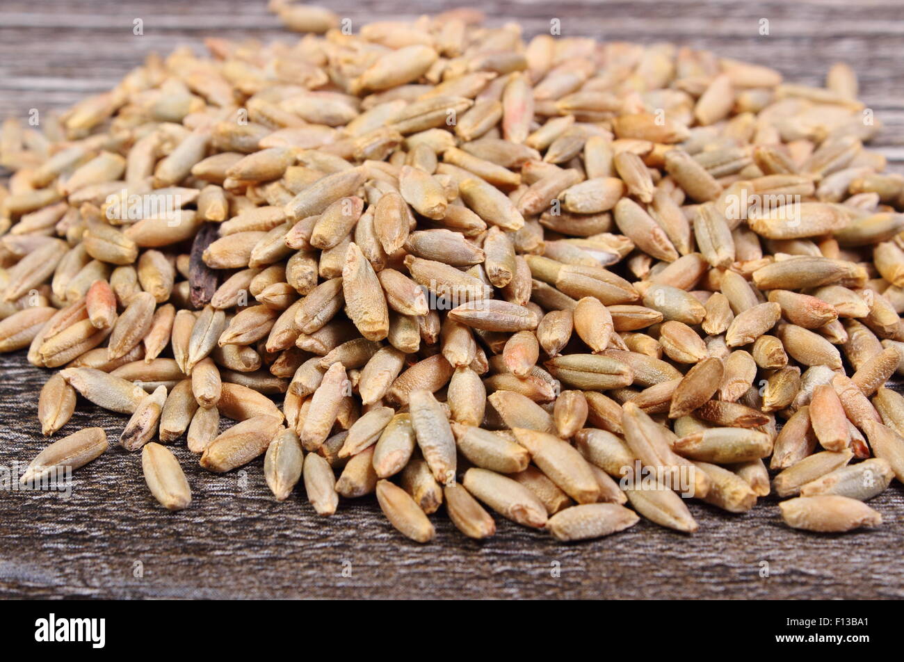 Heap of organic whole rye grain lying on wooden background Stock Photo ...