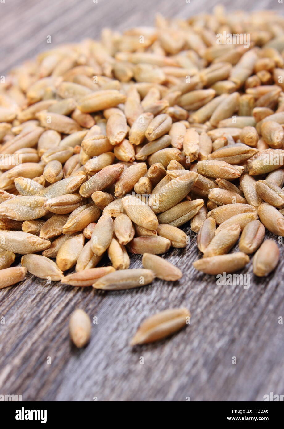 Heap of organic whole rye grain lying on wooden background Stock Photo ...