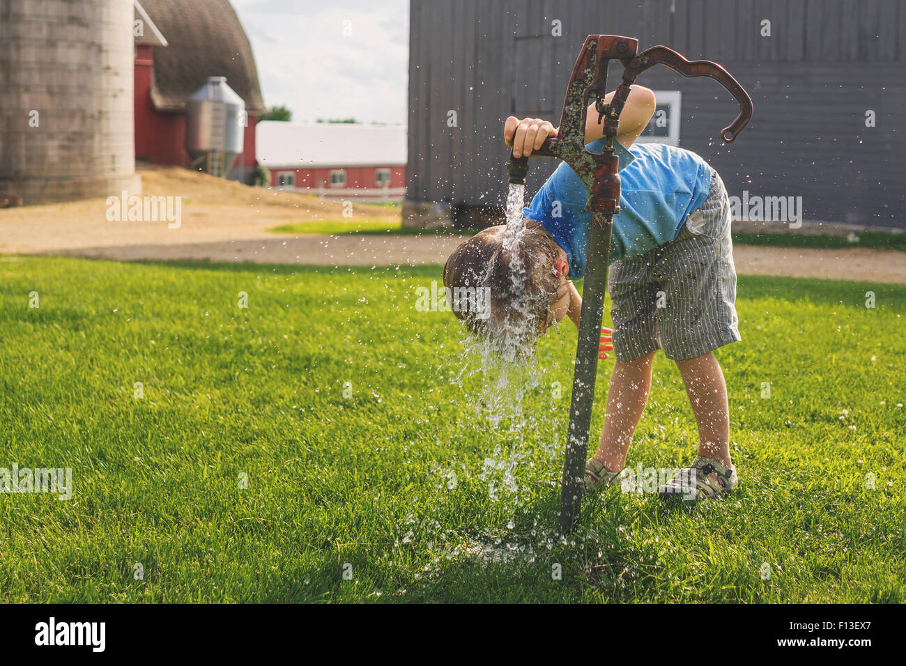 Boy putting his head under a water tap on a farm Stock Photo - Alamy