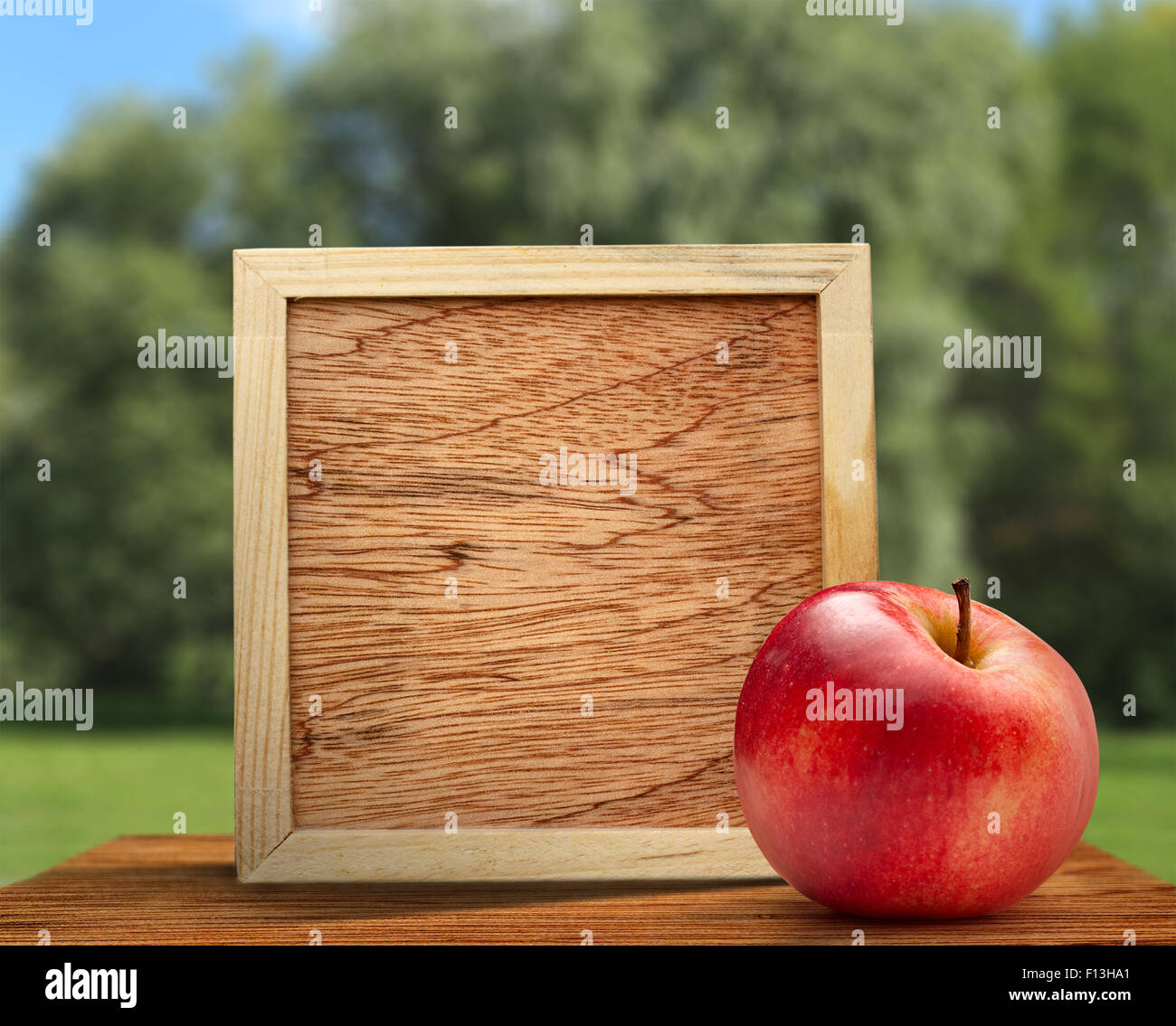 Red apple with wooden frame on nature background Stock Photo - Alamy