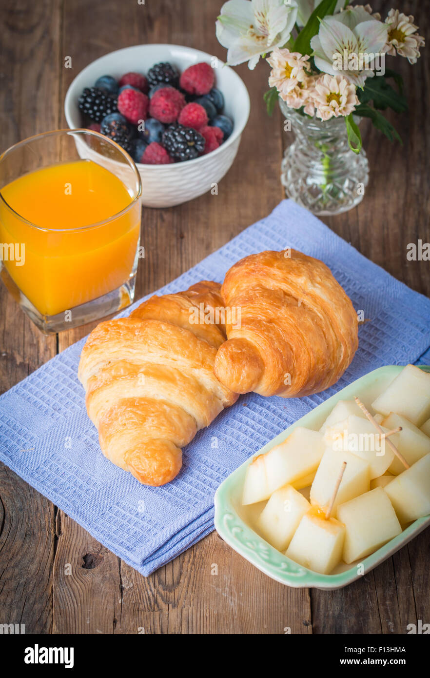Breakfast with orange juice, fresh croissants, melon and ripe berries ...