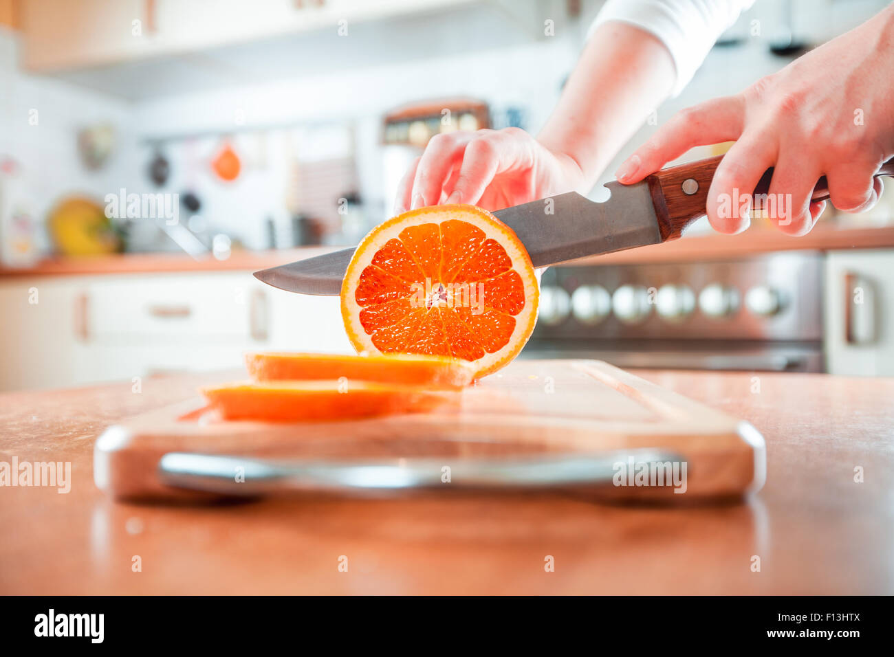 Woman's hands cutting fresh orange on kitchen Stock Photo - Alamy