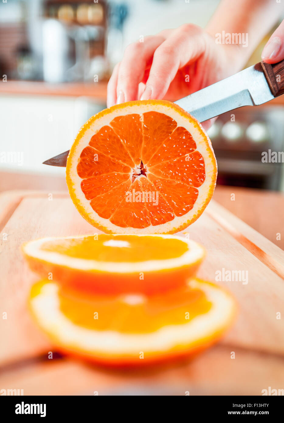 Woman's hands cutting fresh orange on kitchen Stock Photo - Alamy