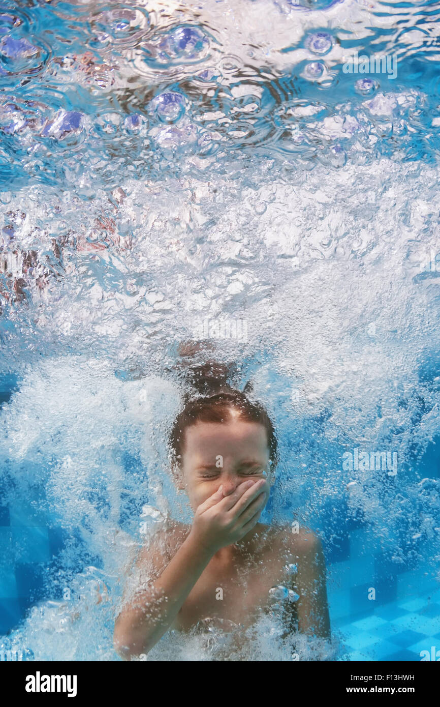Funny face portrait of boy swimming and diving in blue pool with fun ...