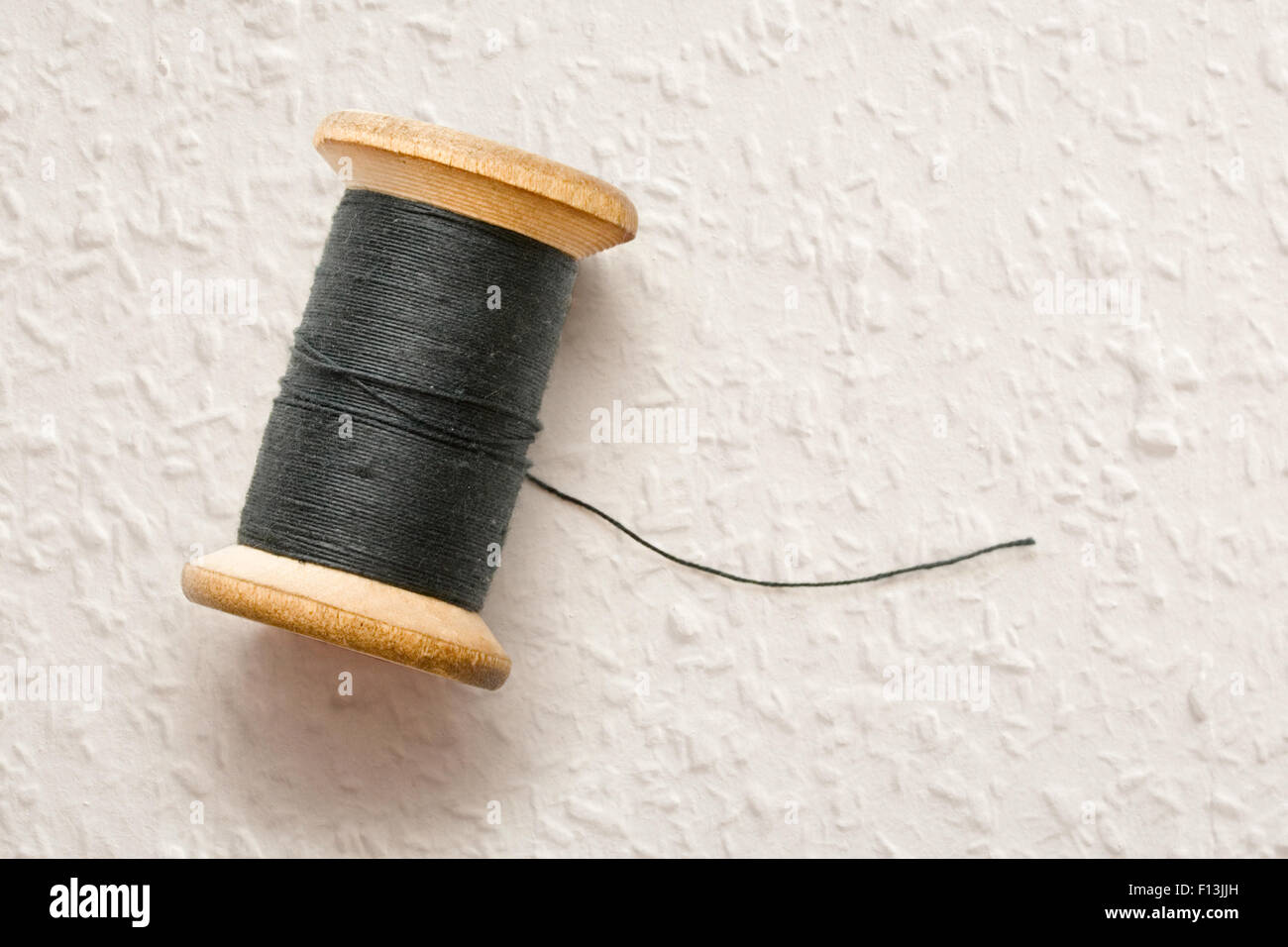 Wooden bobbin of black thread in closeup Stock Photo - Alamy