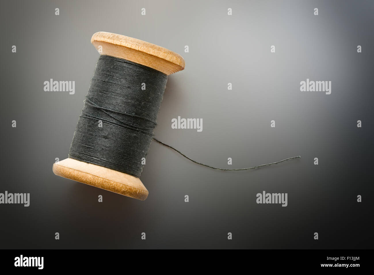 Wooden bobbin of black thread in closeup Stock Photo - Alamy
