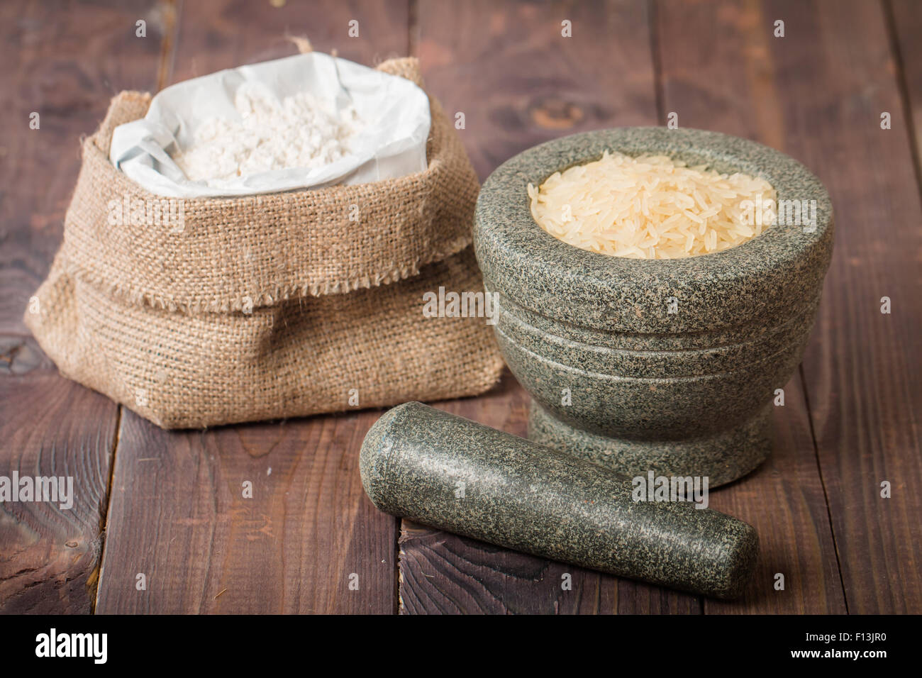 Rice grains in the mortar and flour on wooden background Stock Photo ...