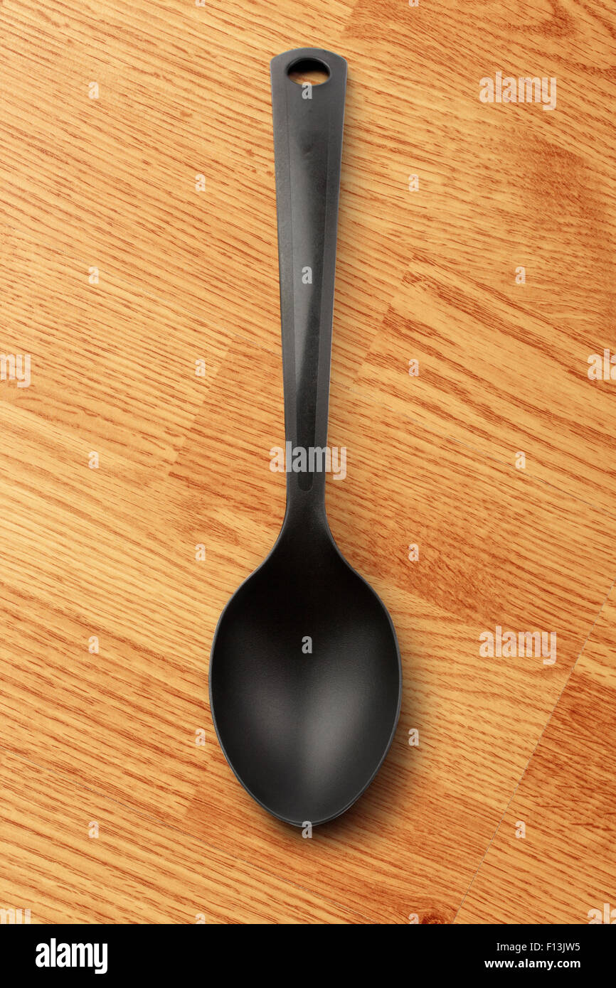 Black plastic kitchen spoon vertical in closeup Stock Photo - Alamy