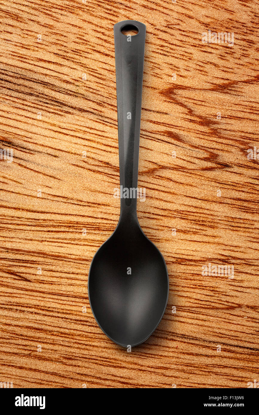 Black plastic kitchen spoon vertical in closeup Stock Photo - Alamy