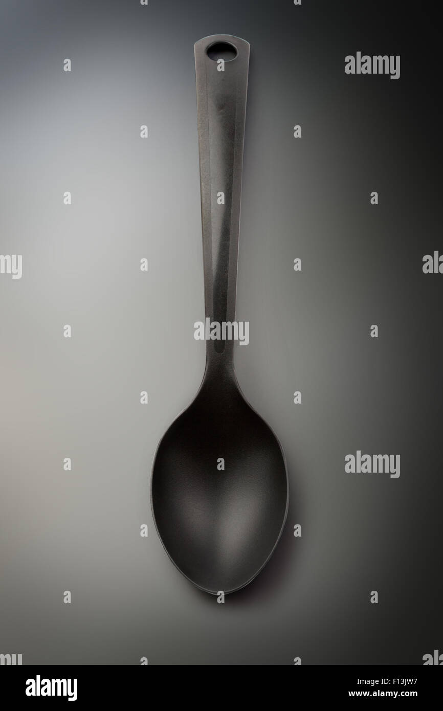 Black plastic kitchen spoon vertical in closeup Stock Photo - Alamy