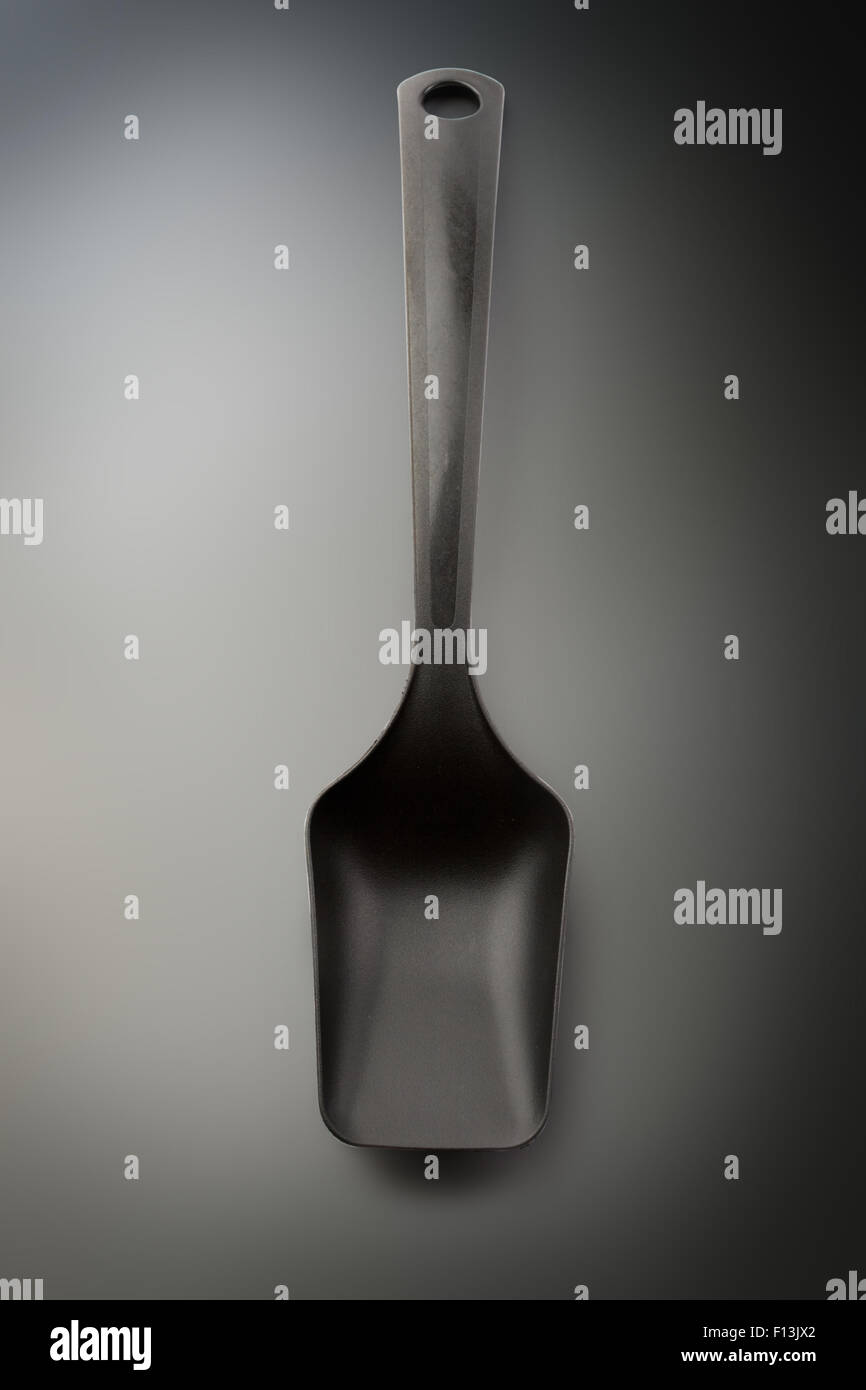 Black plastic kitchen spoon vertical in closeup Stock Photo - Alamy