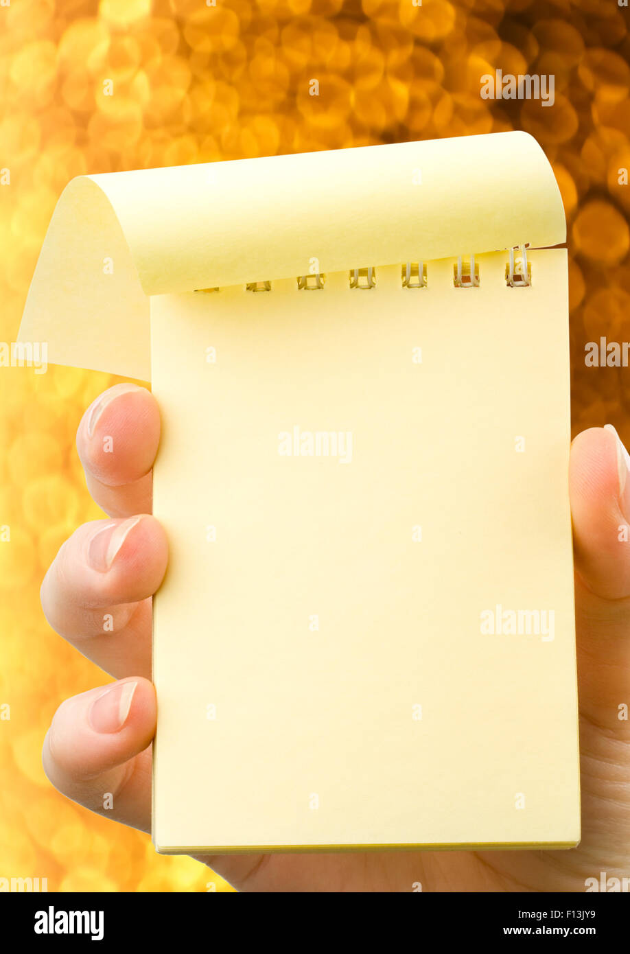Female hand holding blank yellow notepad vertical Stock Photo - Alamy