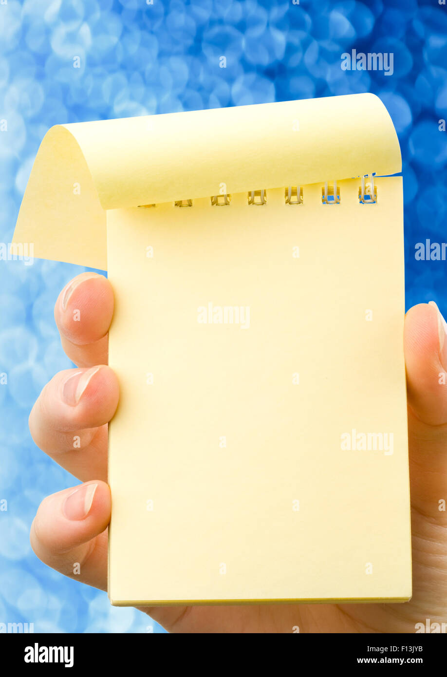 Female hand holding blank yellow notepad vertical Stock Photo - Alamy