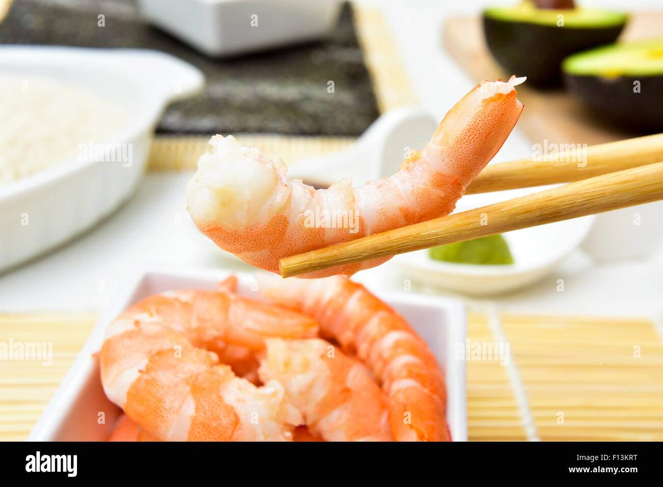 closeup of a shrimp on chopsticks, and some other ingredients and tools ...