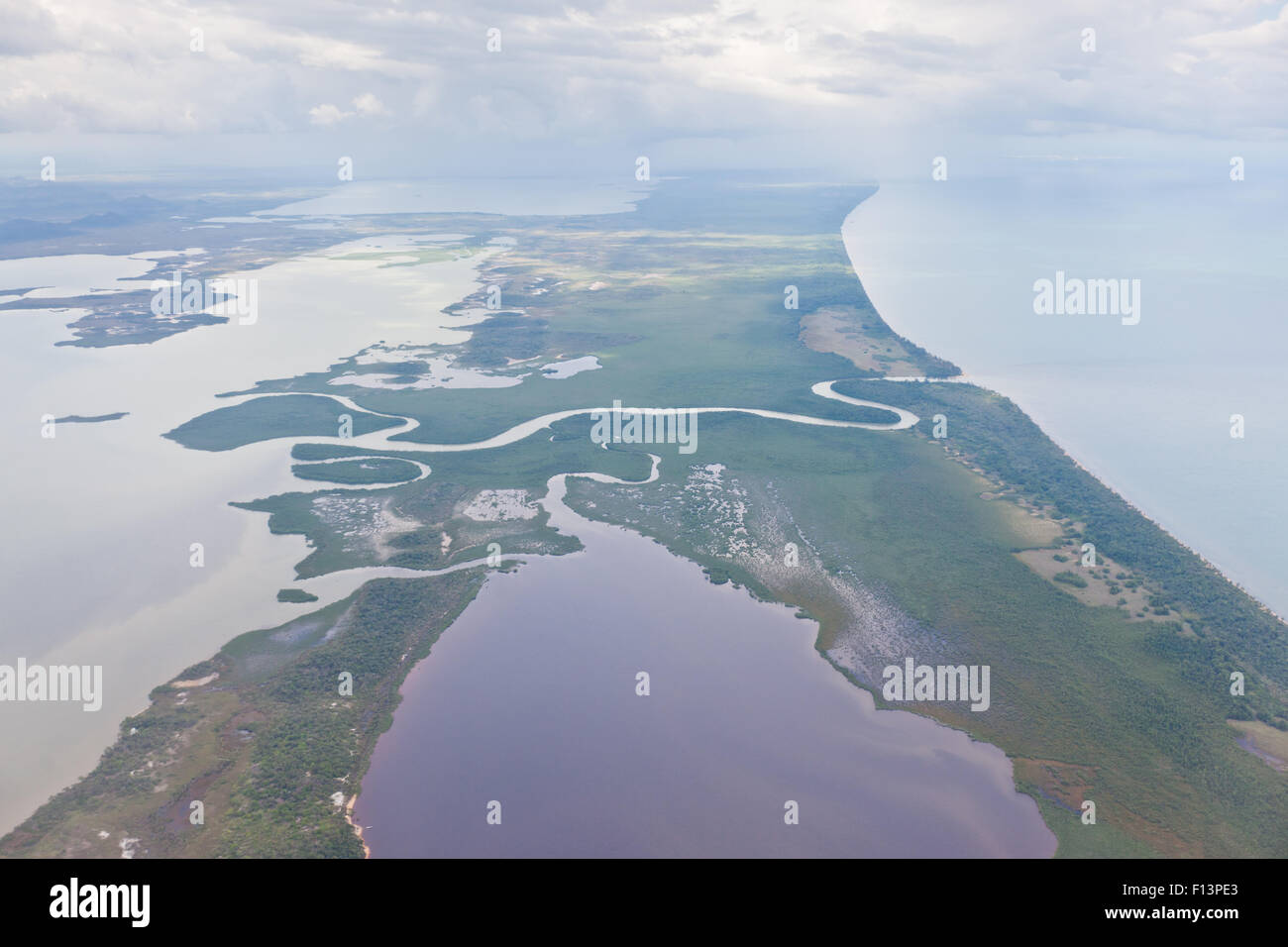 A river outlet curving through tropical jungle from an inland body of ...