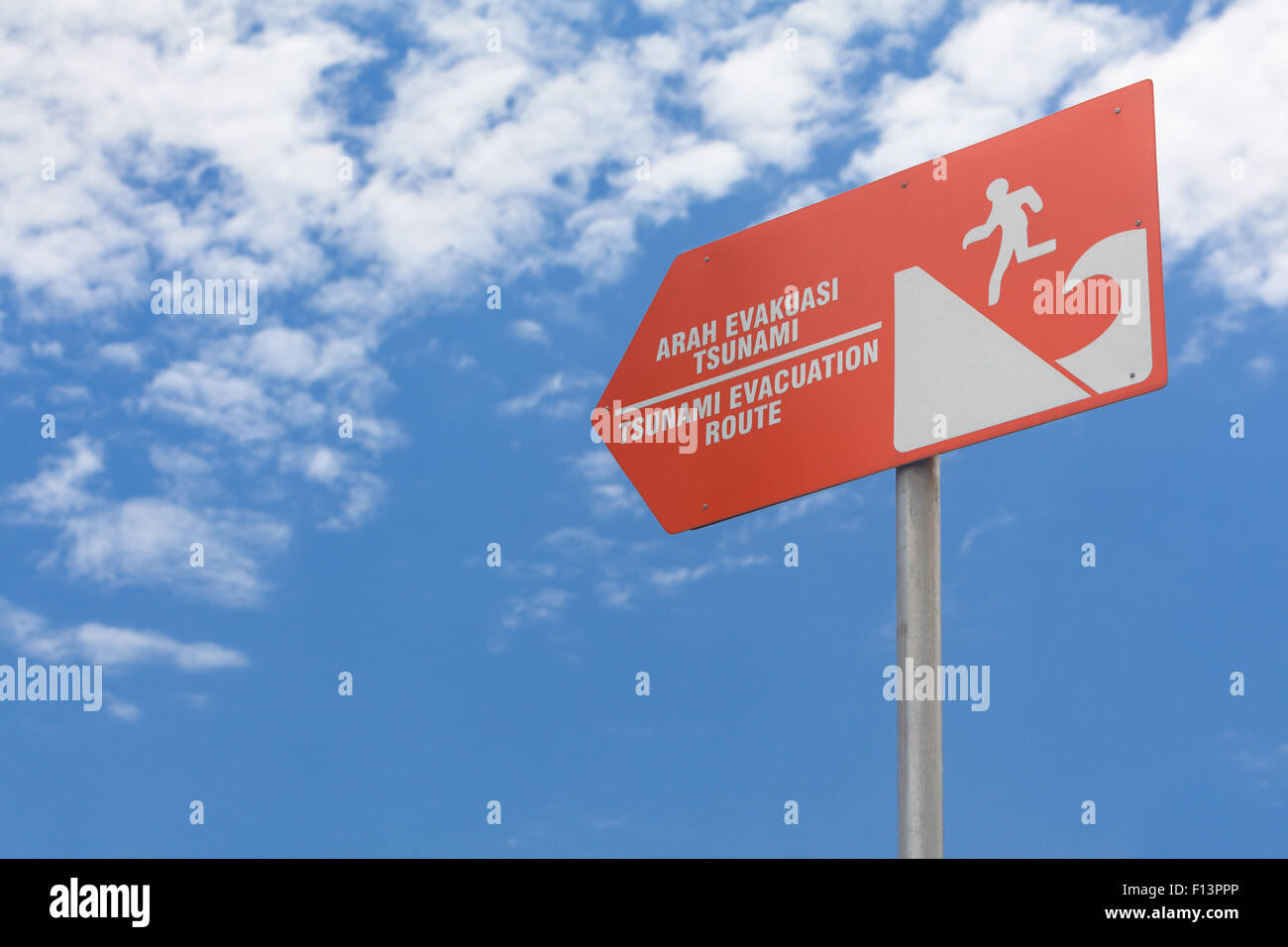 Orange tsunami warning sign "Evacuation route " with picture of waves ...