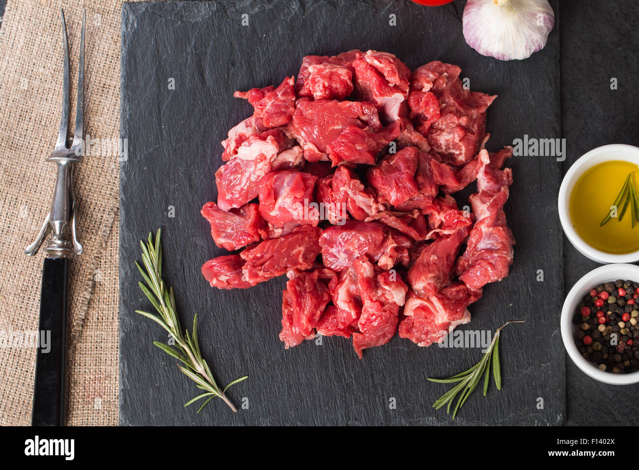 Raw beef cubes with rosemary and beefsteak spices on black background ...