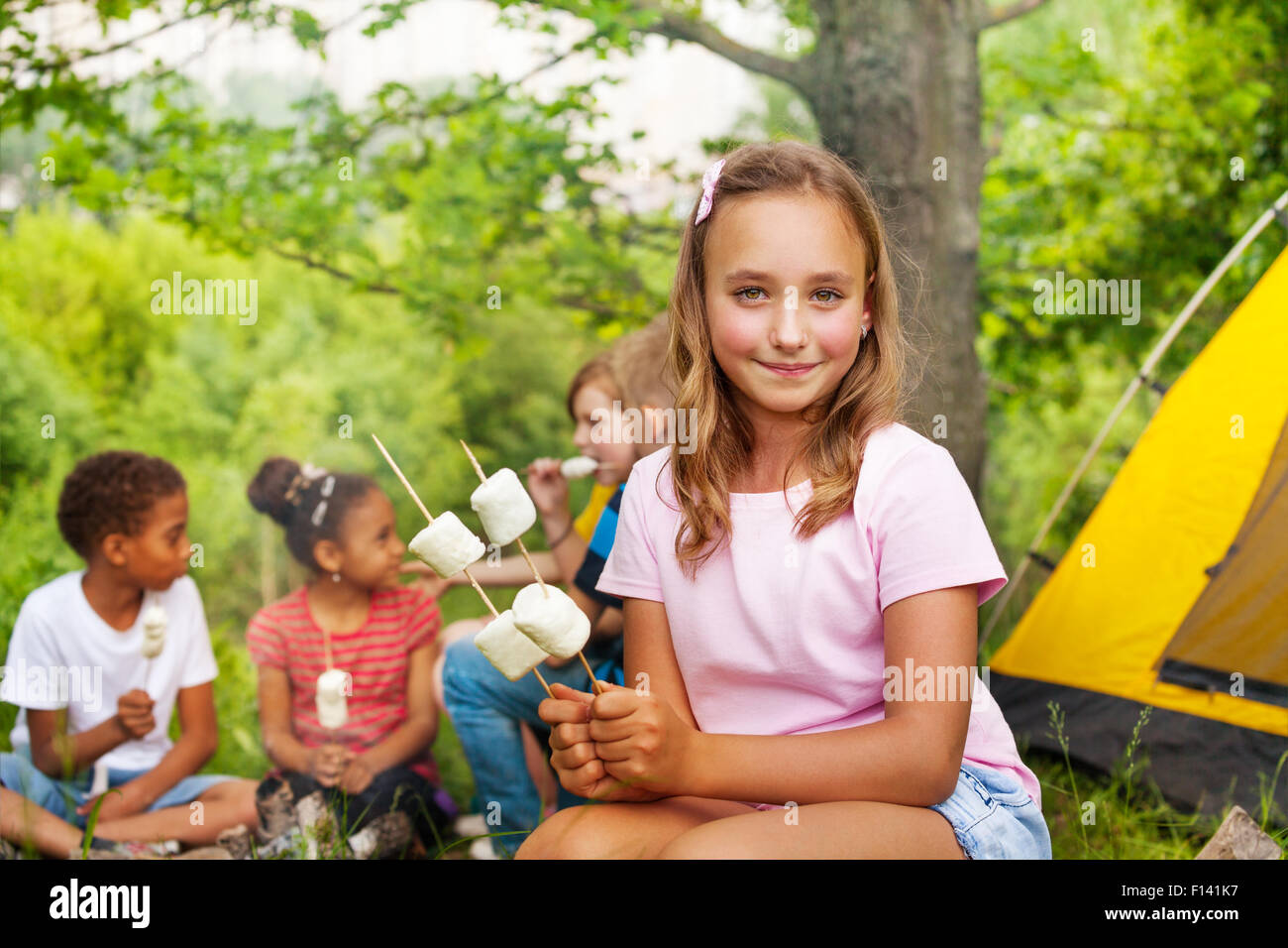 Beautiful girl holds sticks with marshmallows Stock Photo - Alamy