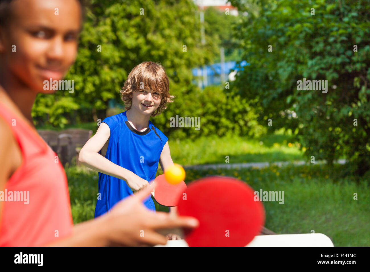 Two smiling friends playing together table tennis Stock Photo - Alamy