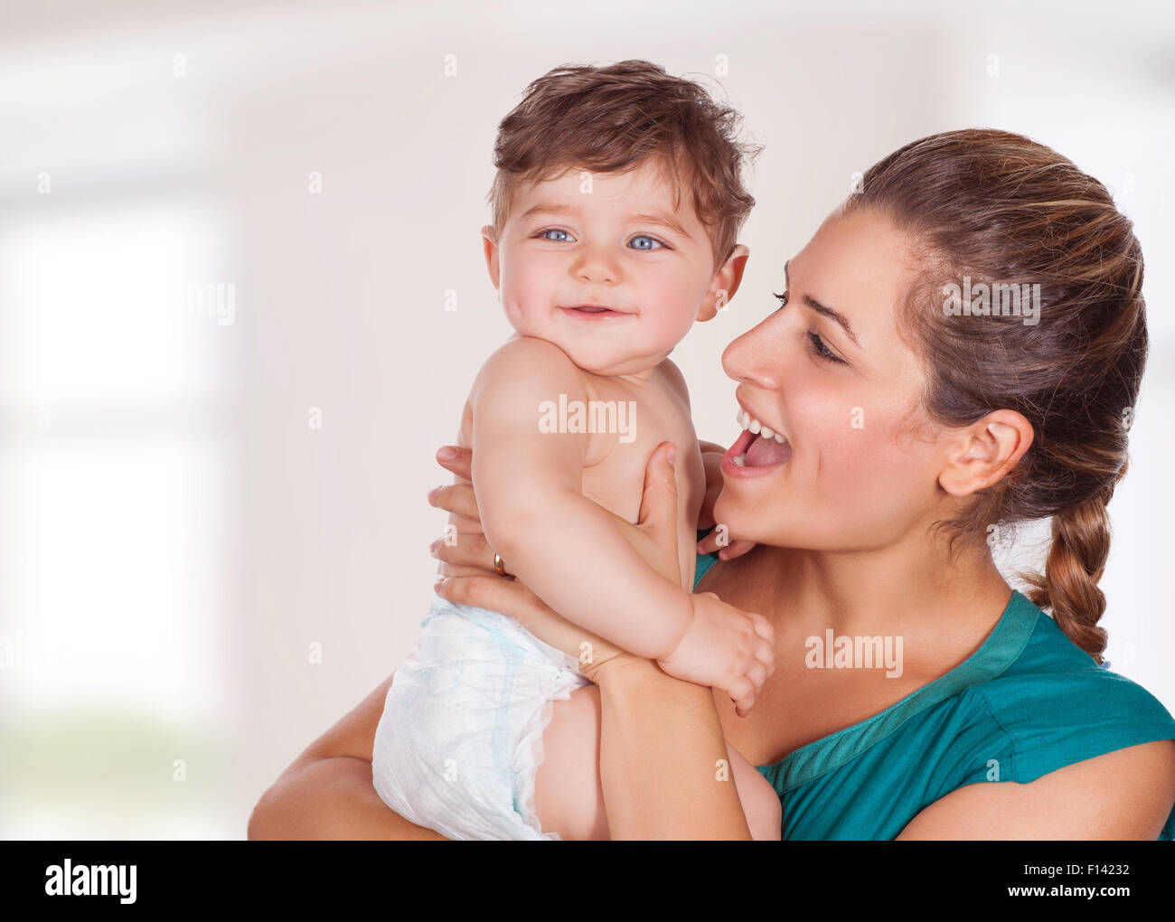 Portrait of beautiful young mother with cute adorable son having fun at home, with pleasure ...