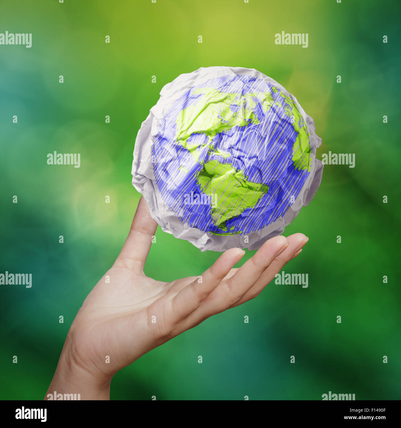 hand showing crumpled world paper symbol as concept on green background ...