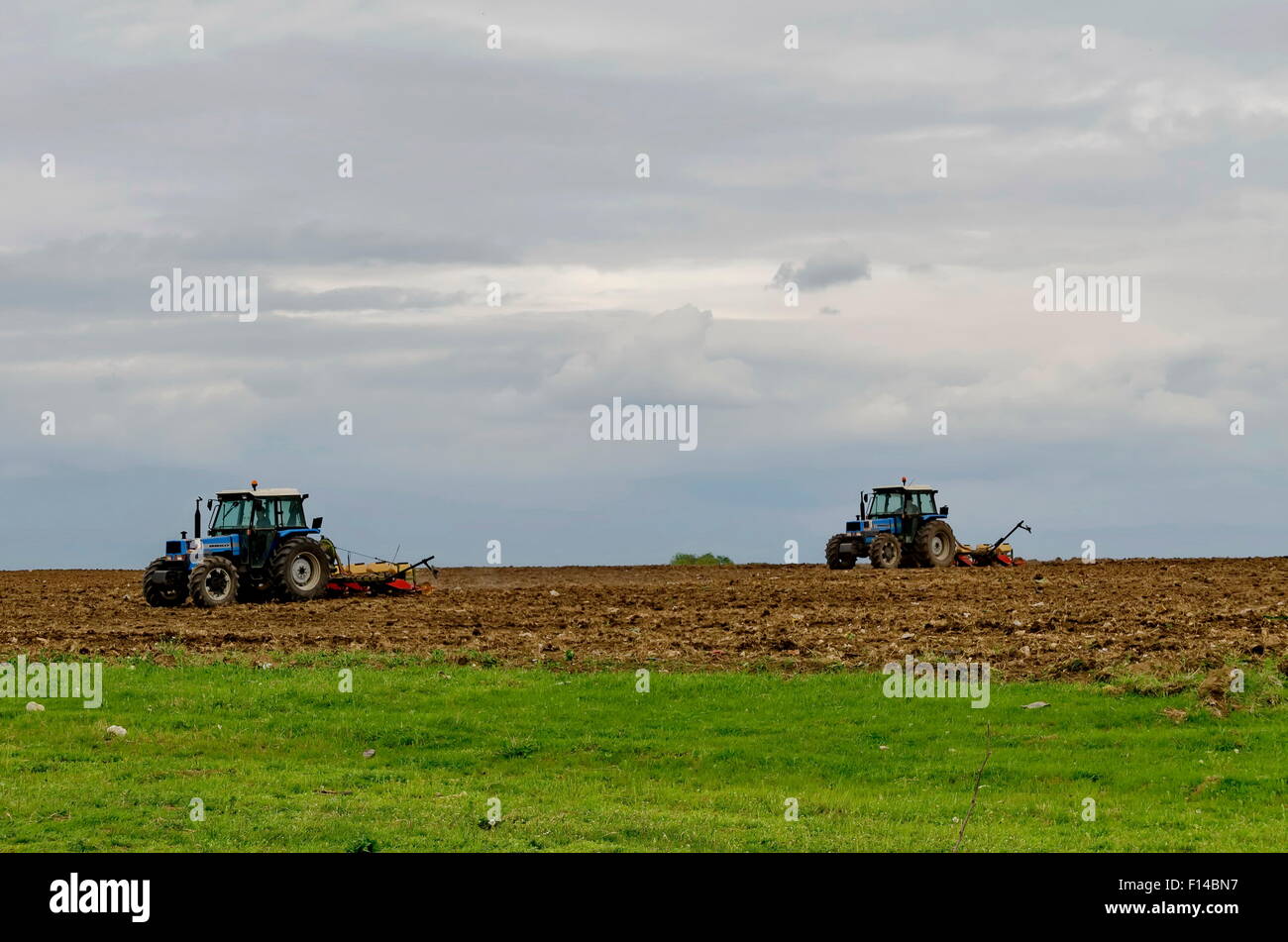 Two tractor with farm machine cultivate the field Stock Photo - Alamy
