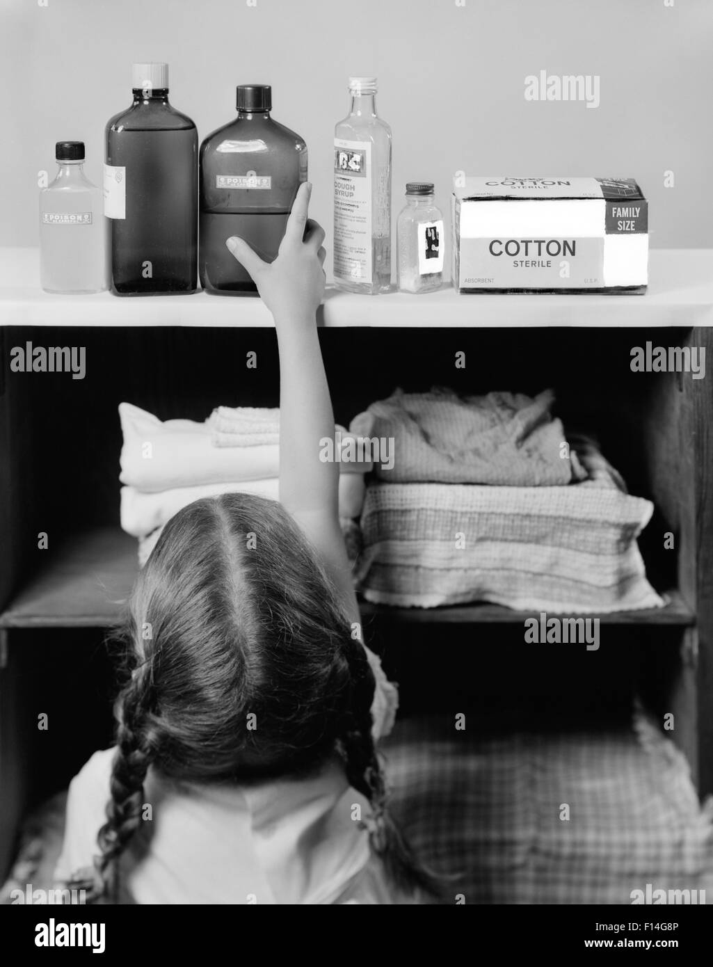 1960s LITTLE GIRL REACHING TO TOP SHELF FOR BOTTLE OF POISON Stock ...