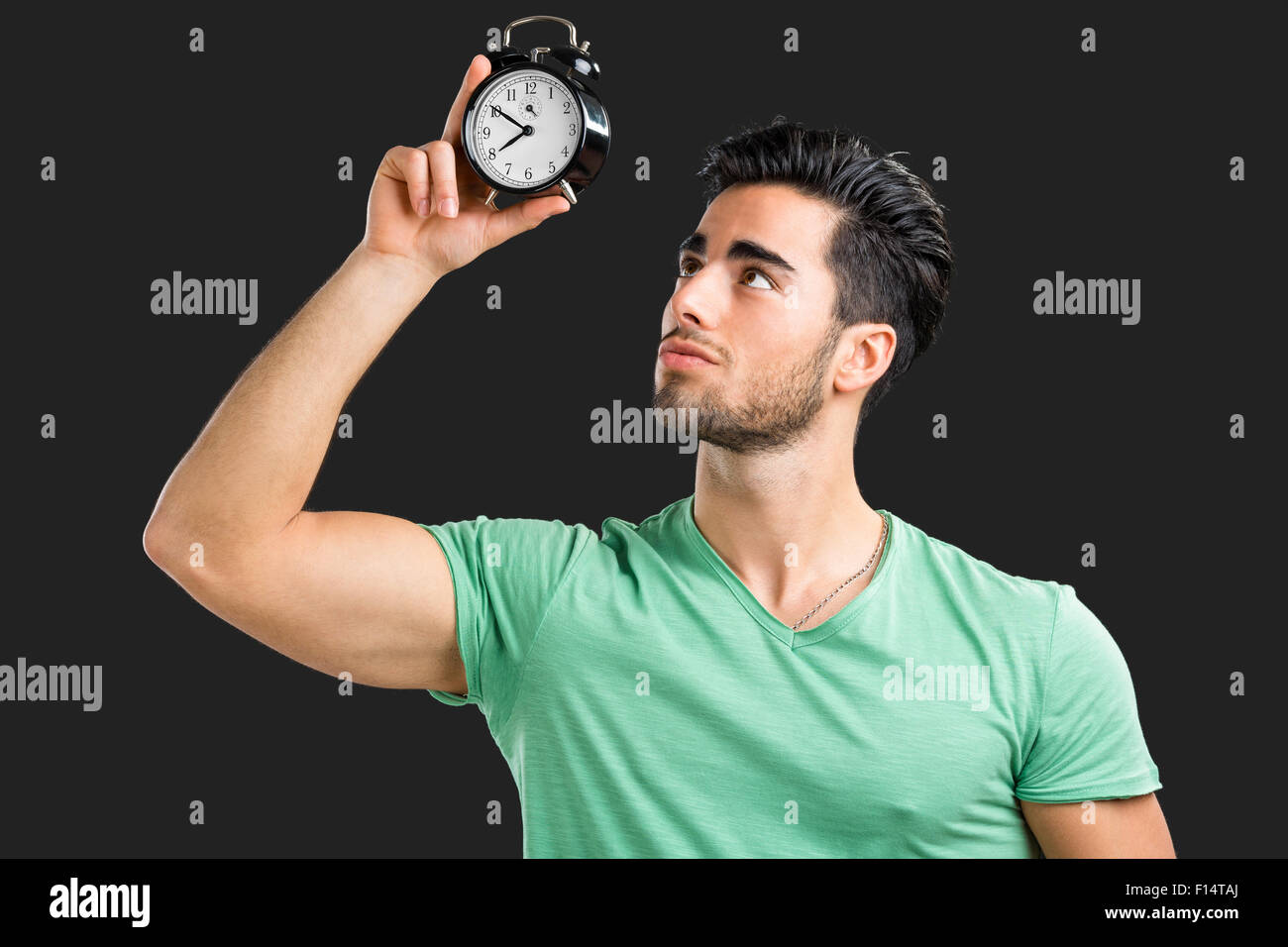 Portrait of handsome young man holding a clock, isolated on gray ...