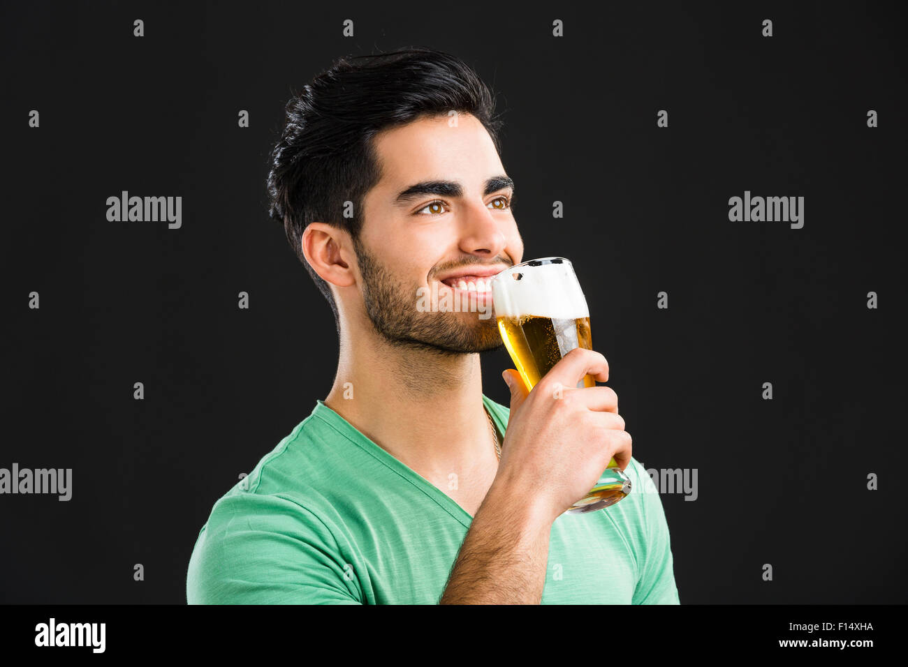 Portrait of handsome young man tasting a draft beer, isolated on gray ...