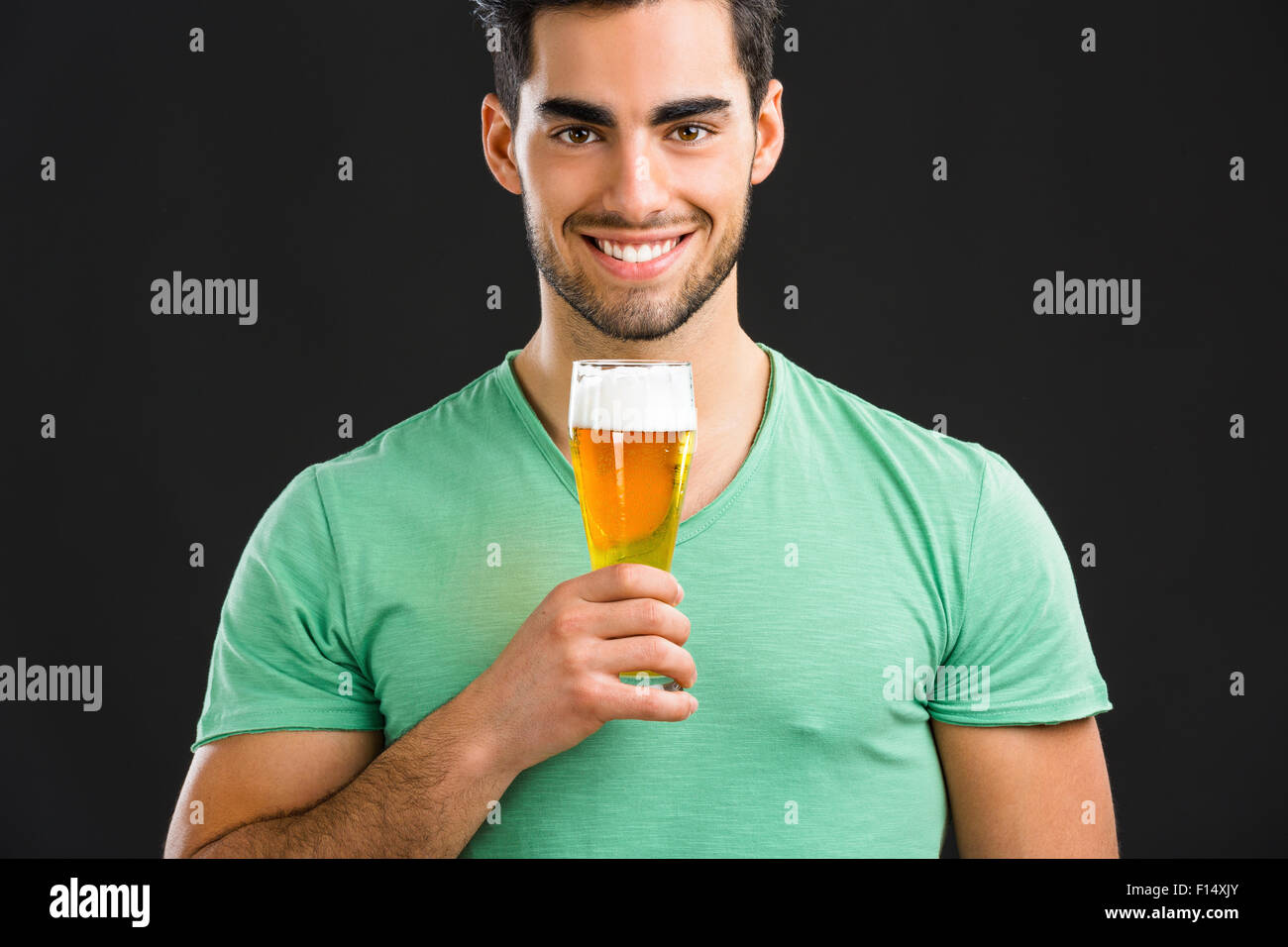 Portrait of handsome young man tasting a draft beer, isolated on gray ...