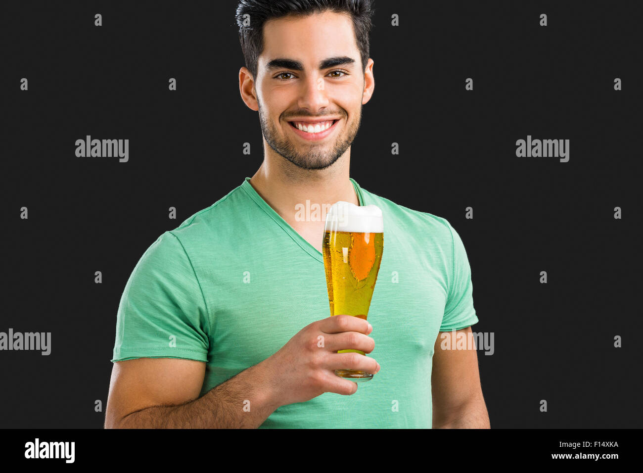 Portrait of handsome young man tasting a draft beer, isolated on gray ...