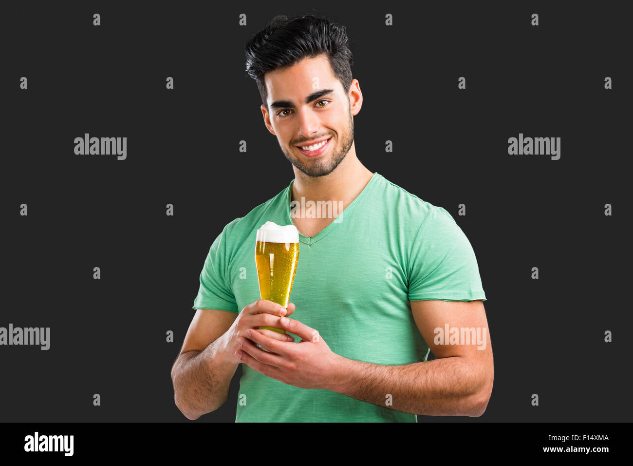 Portrait of handsome young man tasting a draft beer, isolated on gray ...