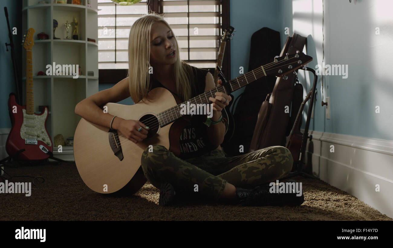 Musical Teenage Girl Singing And Strumming Acoustic Guitar Sitting