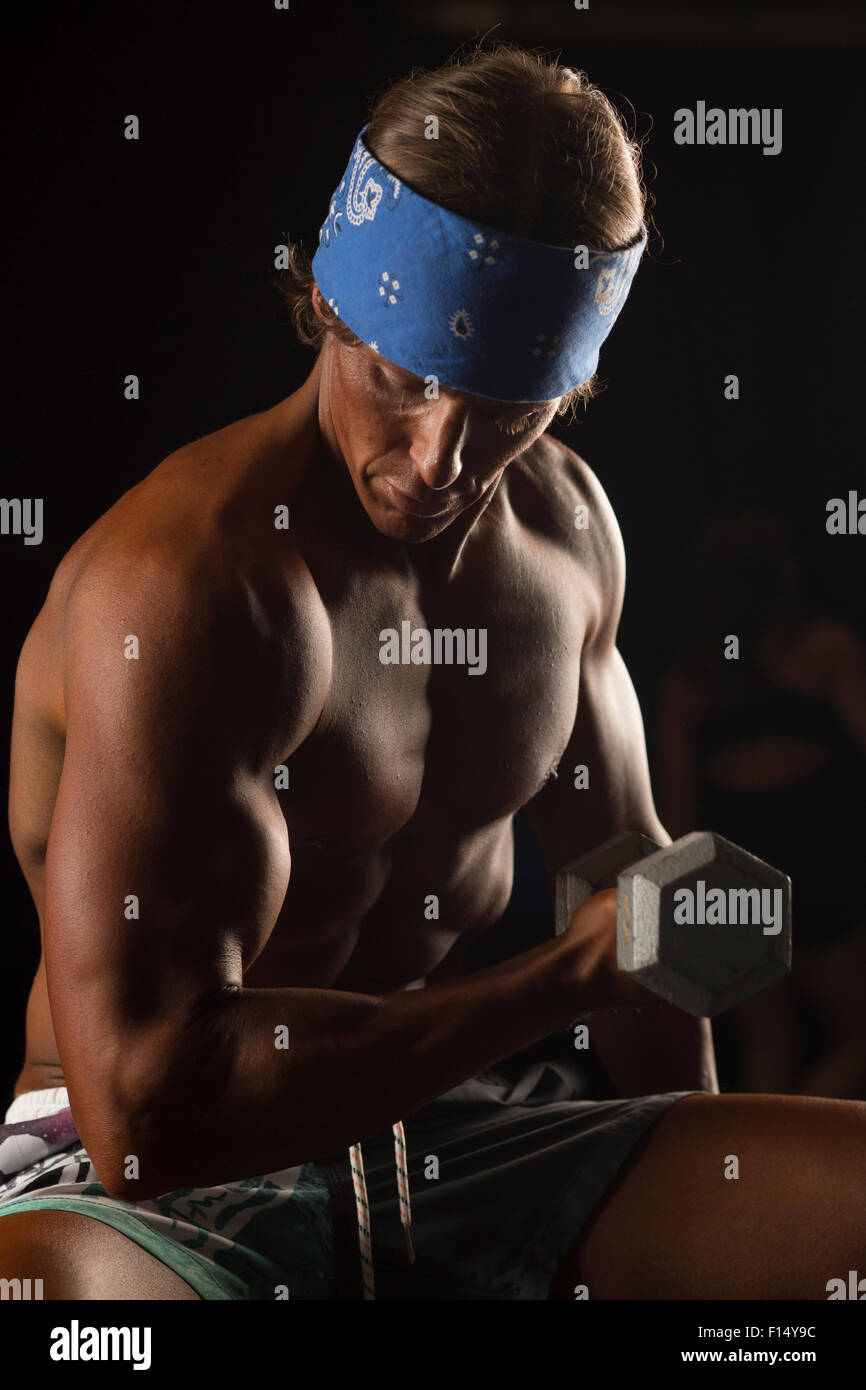 Close up of serious concentrating bodybuilder looking down at biceps ...
