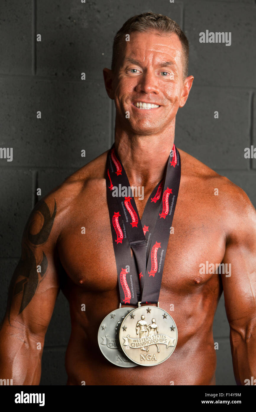 Close up of proud smiling bodybuilder wearing first prize award medals ...