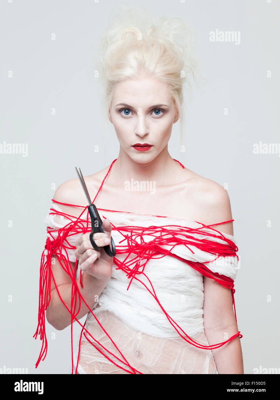 Studio portrait of young woman wrapped in red thread Stock Photo - Alamy