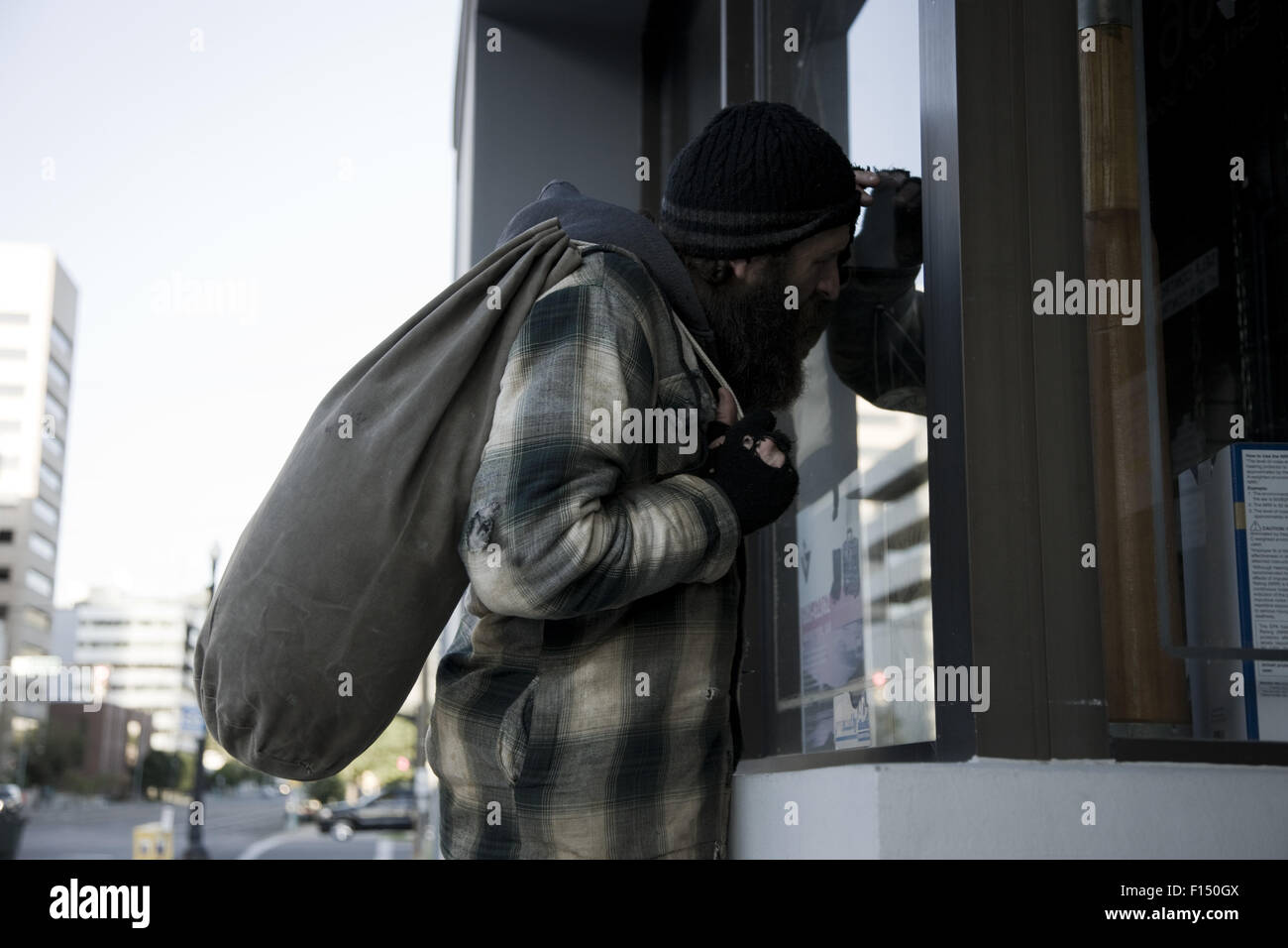USA, Utah, Salt Lake City, Homeless man looking through window holding ...