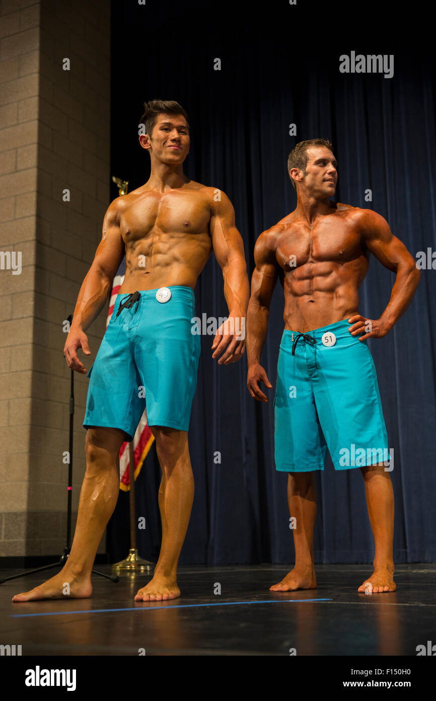 Proud bodybuilders in shorts flexing muscles on stage at competition ...