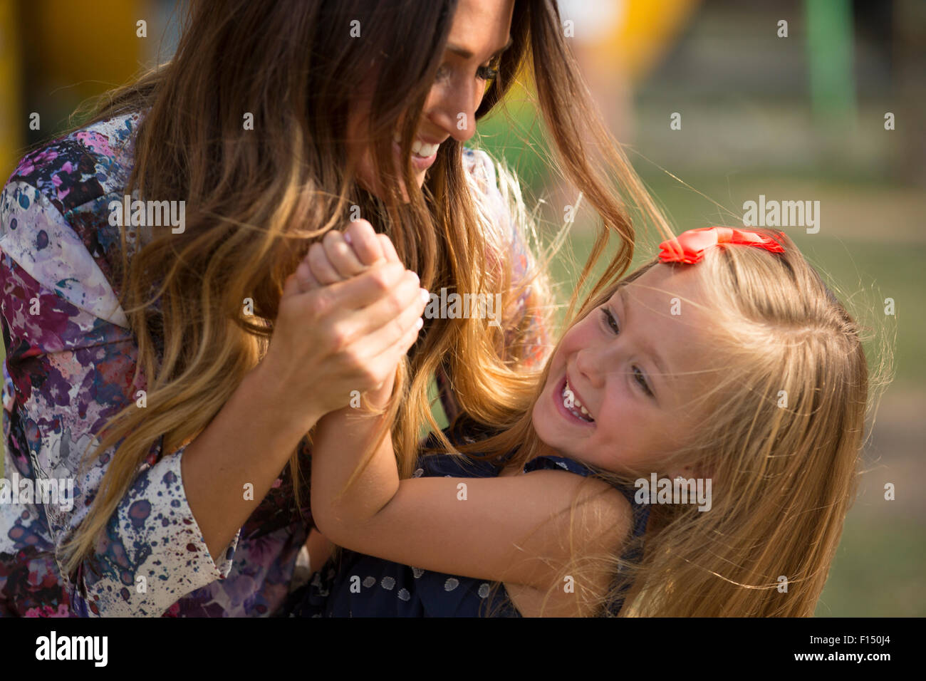 Close up of happy laughing mother with long hair playing with daughter ...