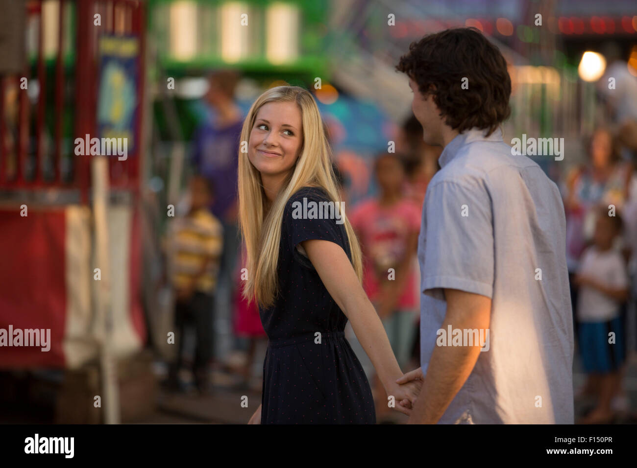 Happy couple holding hands and exploring at amusement park fun fair ...