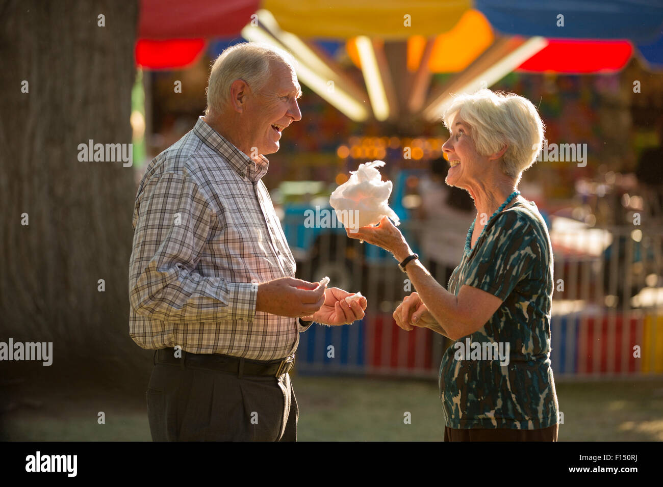 Happy fun couple sharing cotton candy snack at amusement park fun fair ...