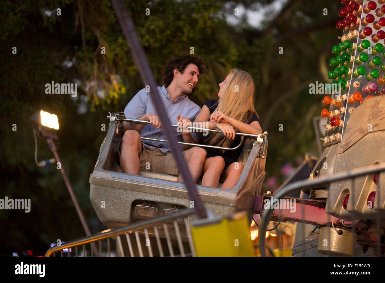 Happy playful couple sitting on amusement park ride at fun fair Stock ...