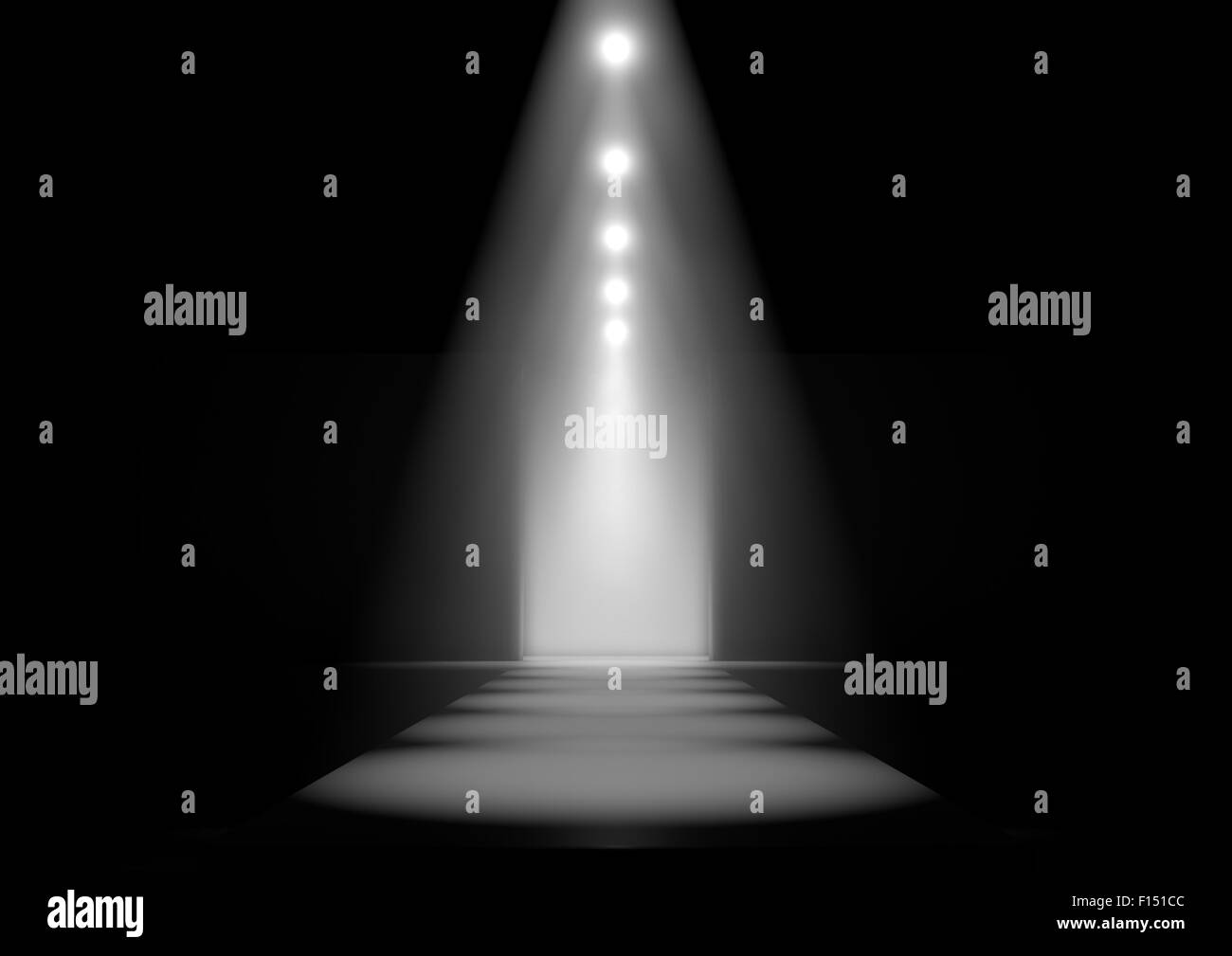 A fashion runway stage lit by a row of spotlights on a dark background ...