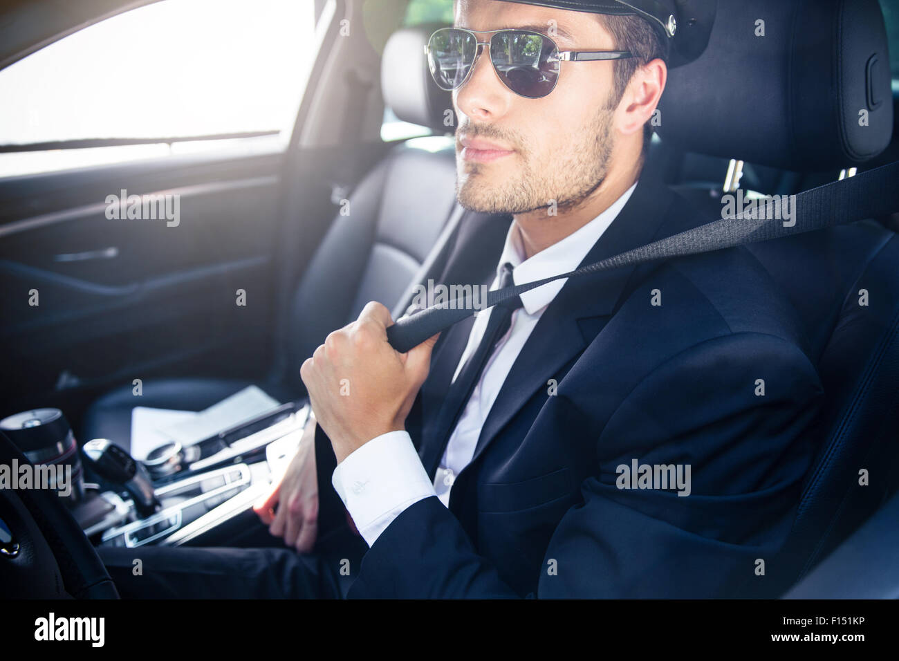 Portrait of a handsome male chauffeur in sunglasses sitting in a car ...